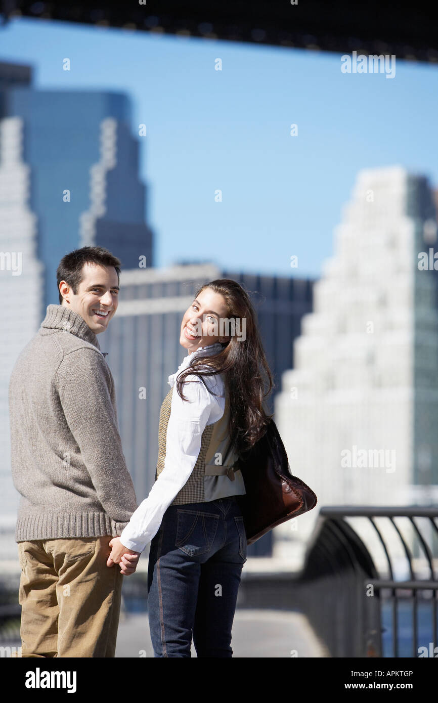 Couple holding hands and looking over shoulder (rear view), New York ...
