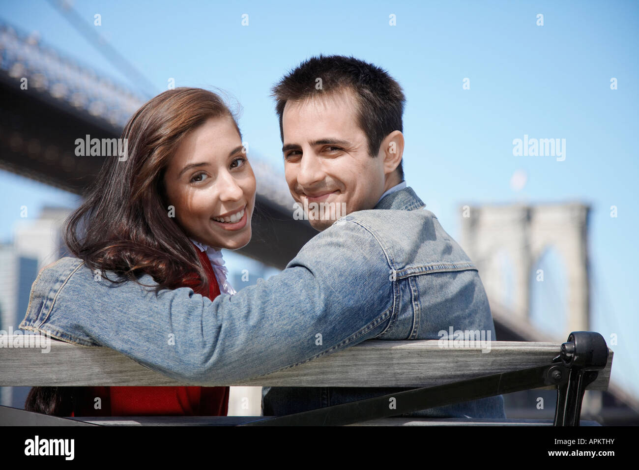 Young couple sitting on bench, looking over shoulders (rear view ...
