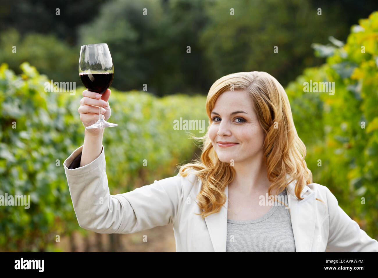 Young woman holding glass of red wine in vineyard (portrait Stock Photo ...