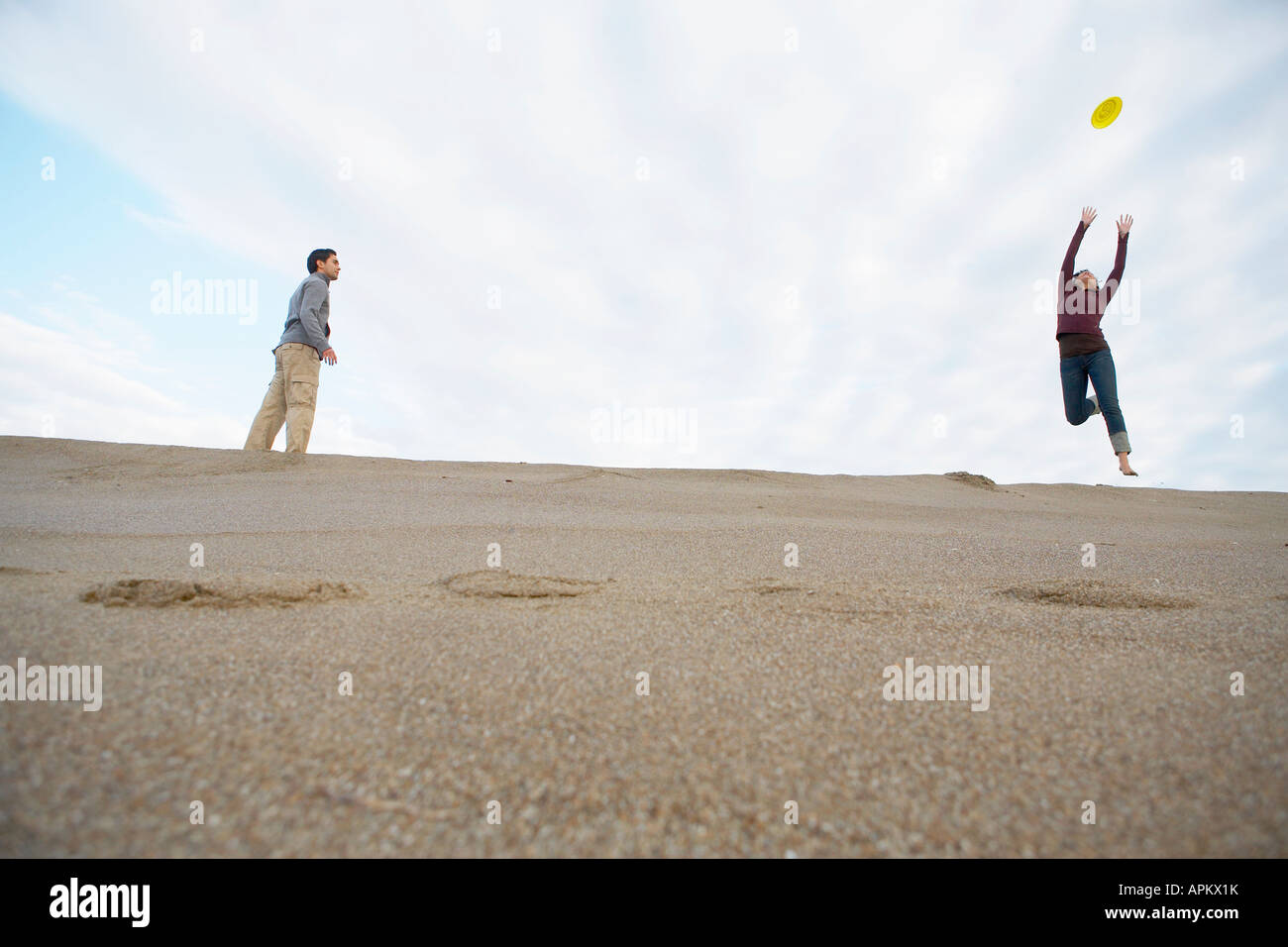 Man and woman throwing frisbee on beach (low angle view Stock Photo - Alamy
