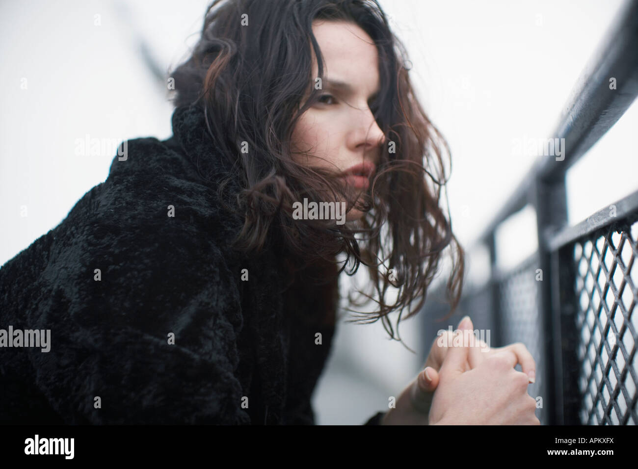 Young woman looking through fence Stock Photo - Alamy