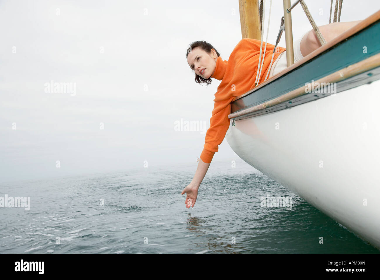 Young woman leaning over boat side, touching water (low angle view ...