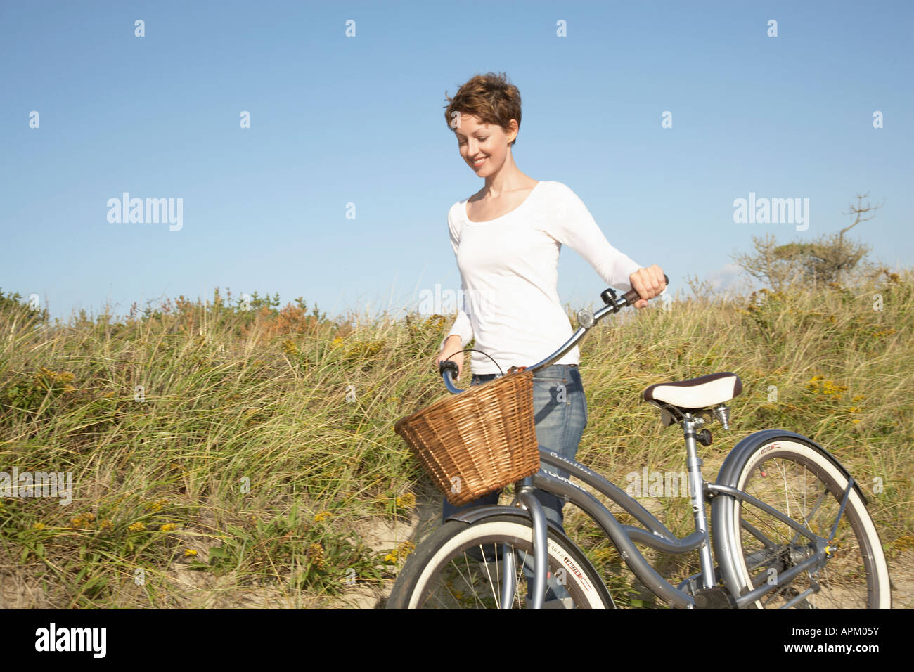 Mid adult woman with bicycle walking on path Stock Photo - Alamy