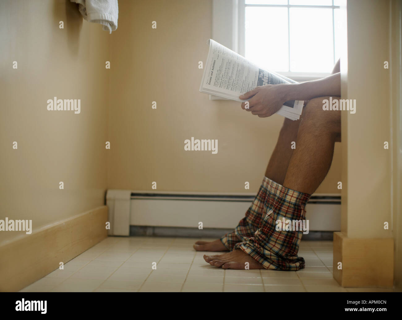 Young man reading in toilet Stock Photo - Alamy
