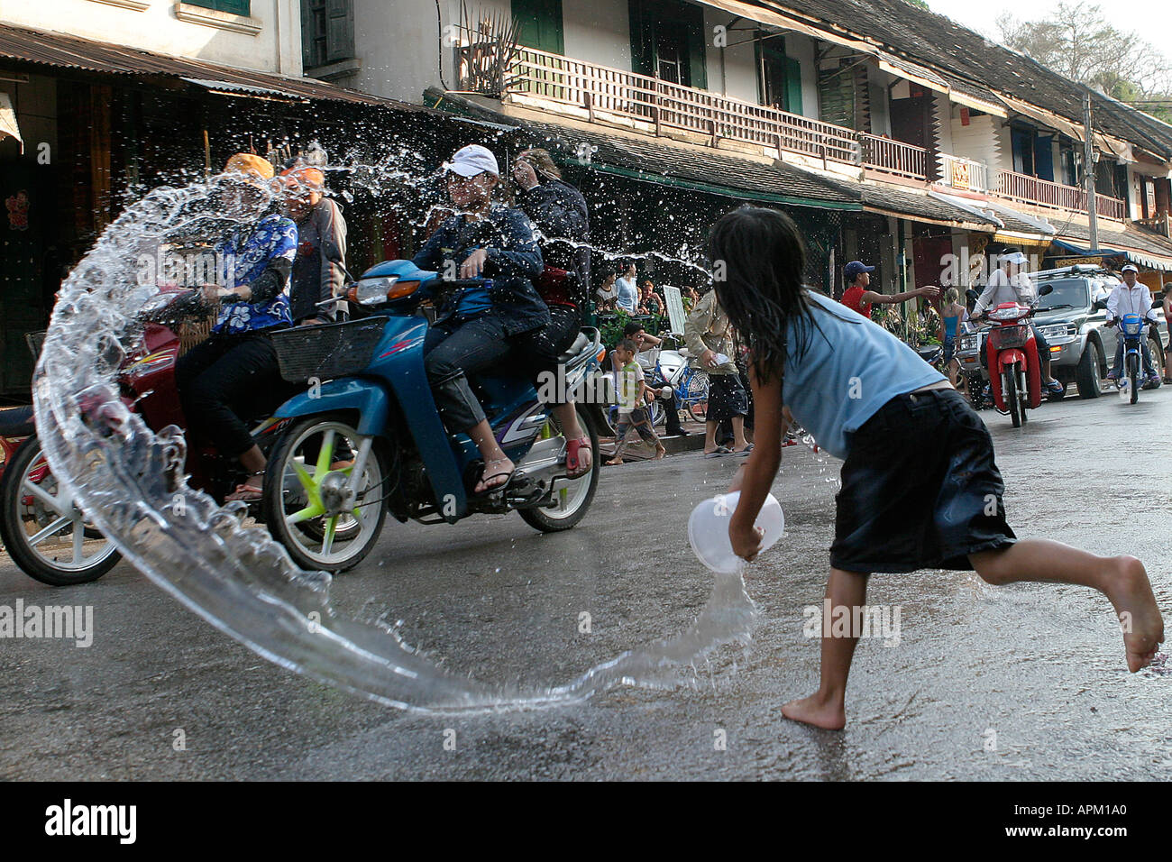 a girl throws an arc of water splash at passing drivers for new years ...