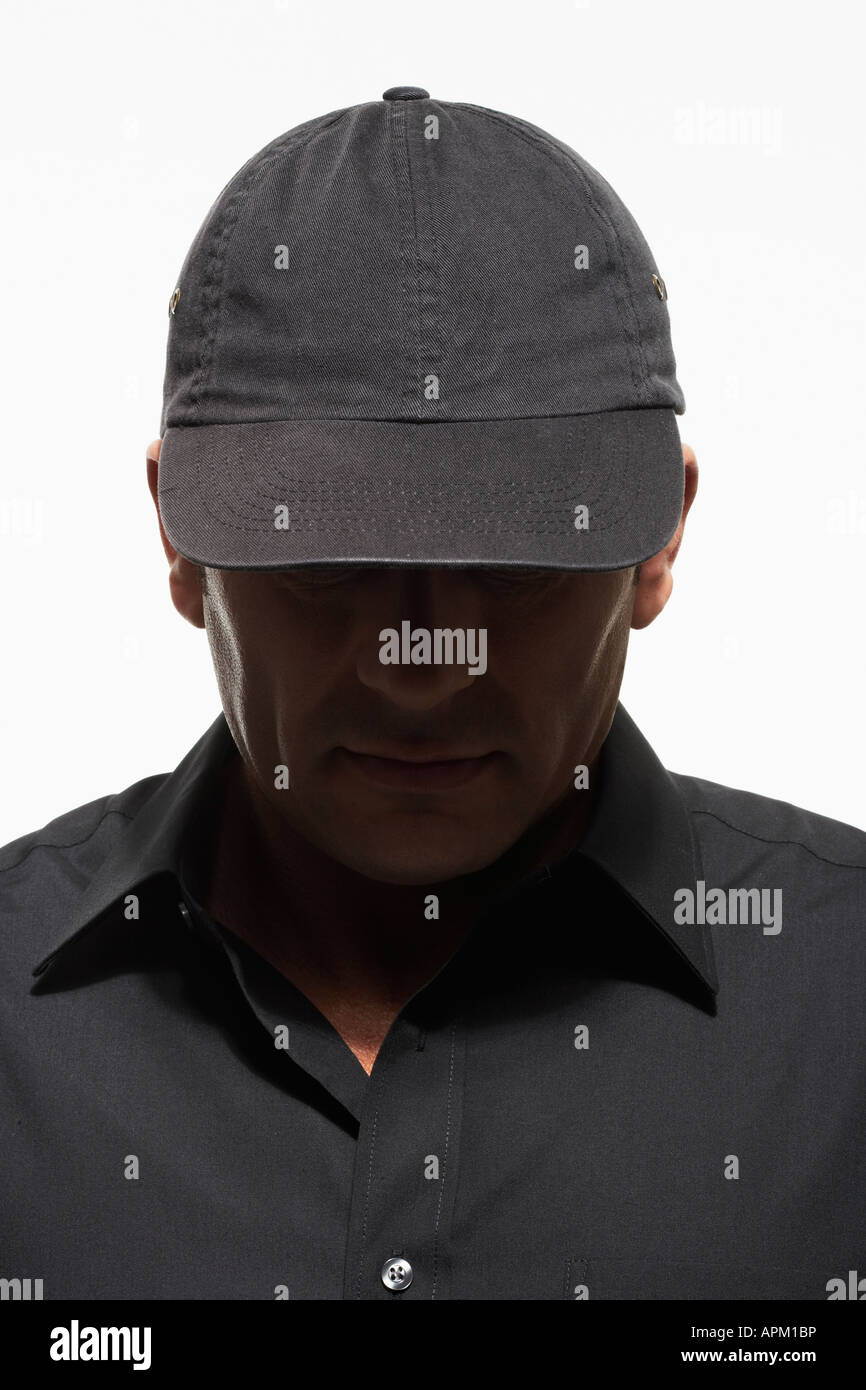 Man in black shirt and cap looking down, portrait Stock Photo - Alamy