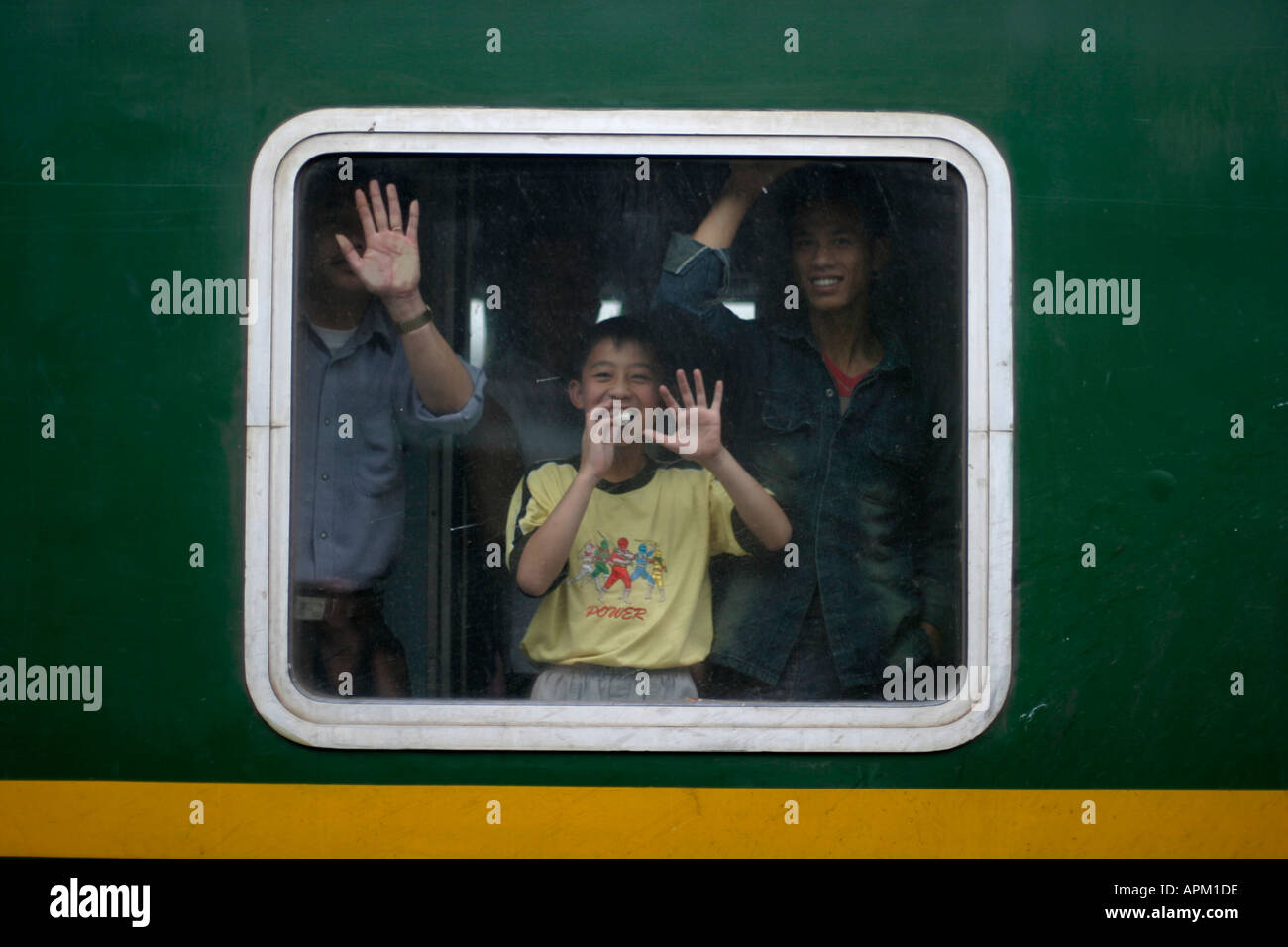 three boys wave goodbye and farewell from the window inside a green ...