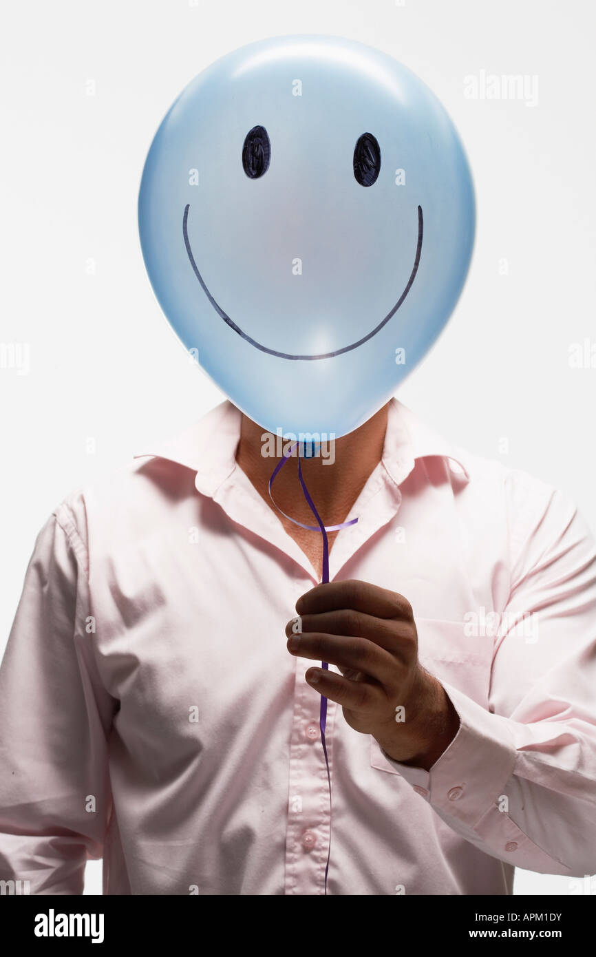 Man holding balloon with smiley face in front of his face Stock Photo ...