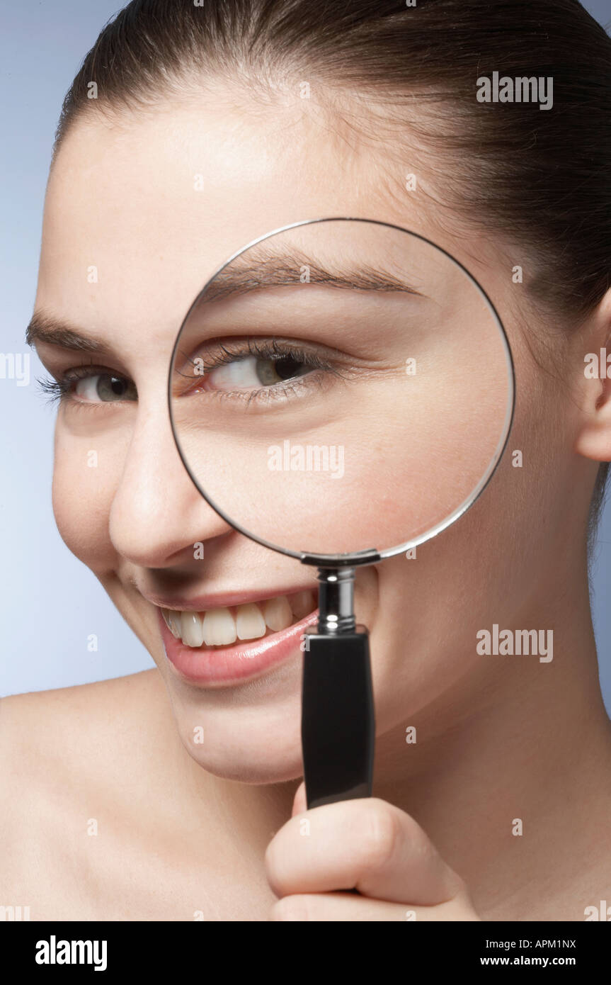 Young woman looking through magnifying glass Stock Photo - Alamy