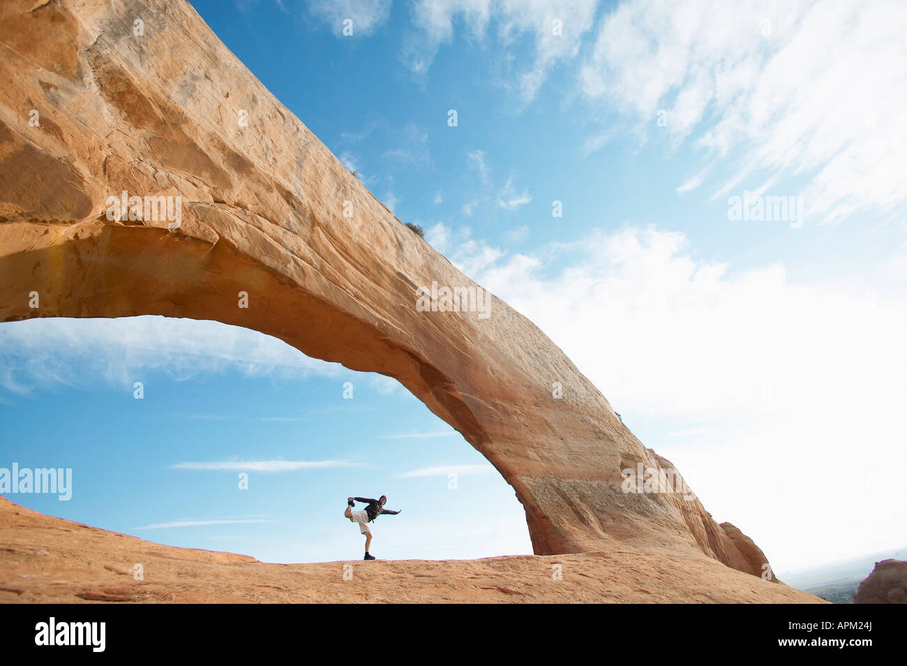 Man stretching under arched rock Stock Photo - Alamy