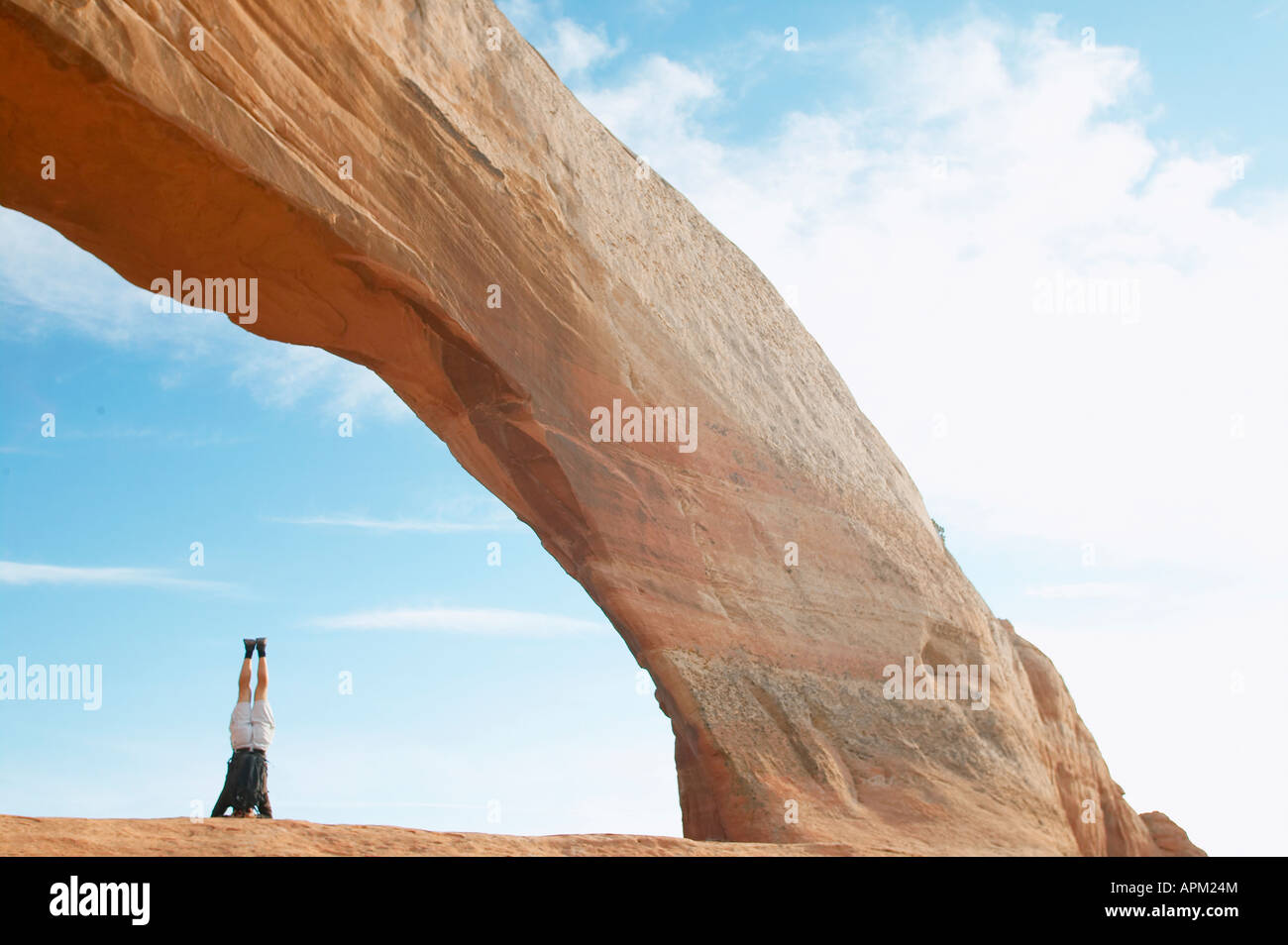 Man standing on head under arched rock Stock Photo - Alamy