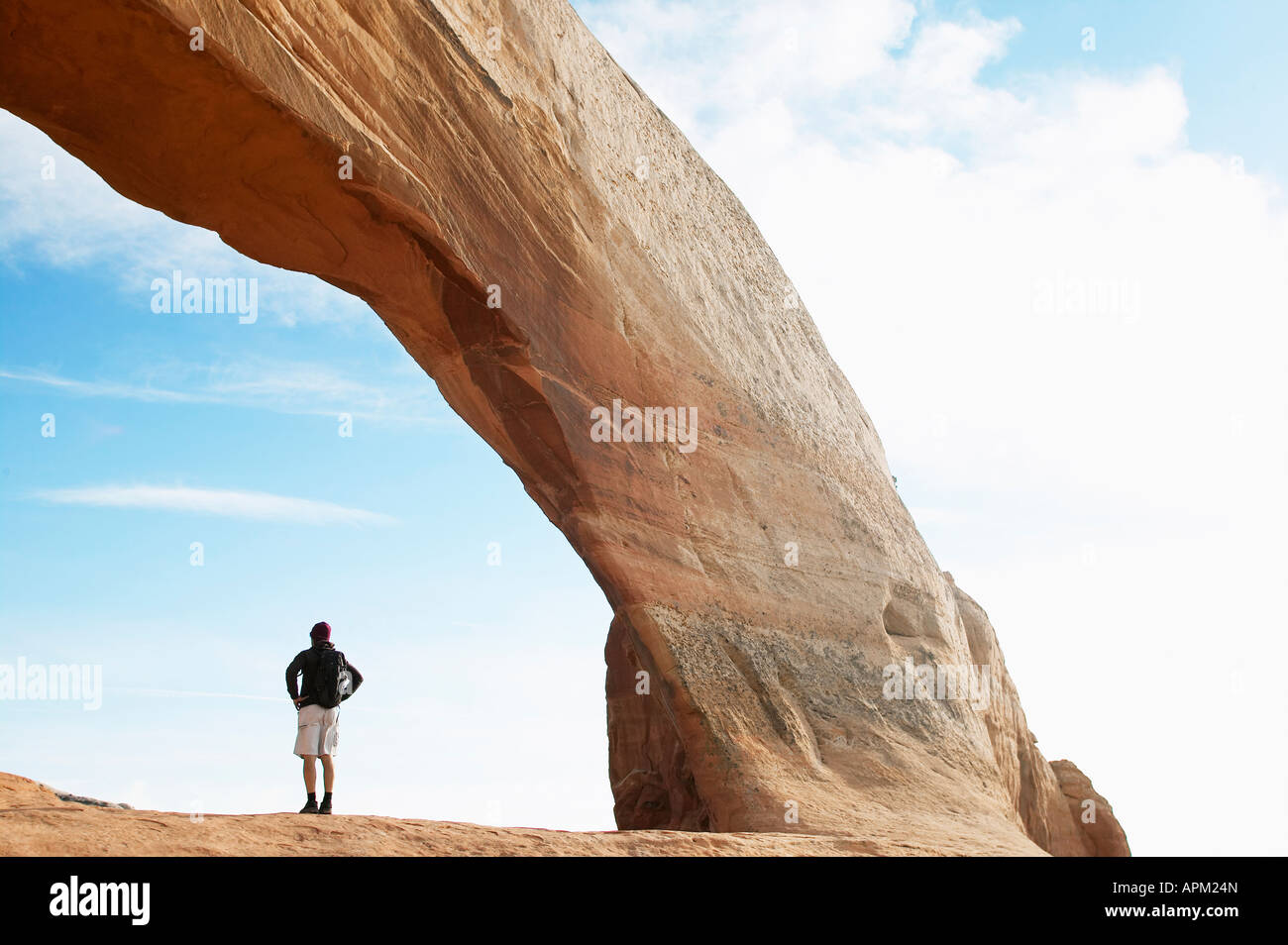 Man standing under arched rock Stock Photo - Alamy