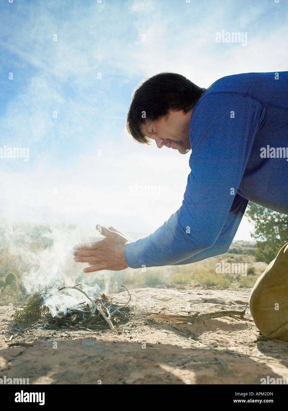 Man lighting fire on rock, low angle view Stock Photo - Alamy