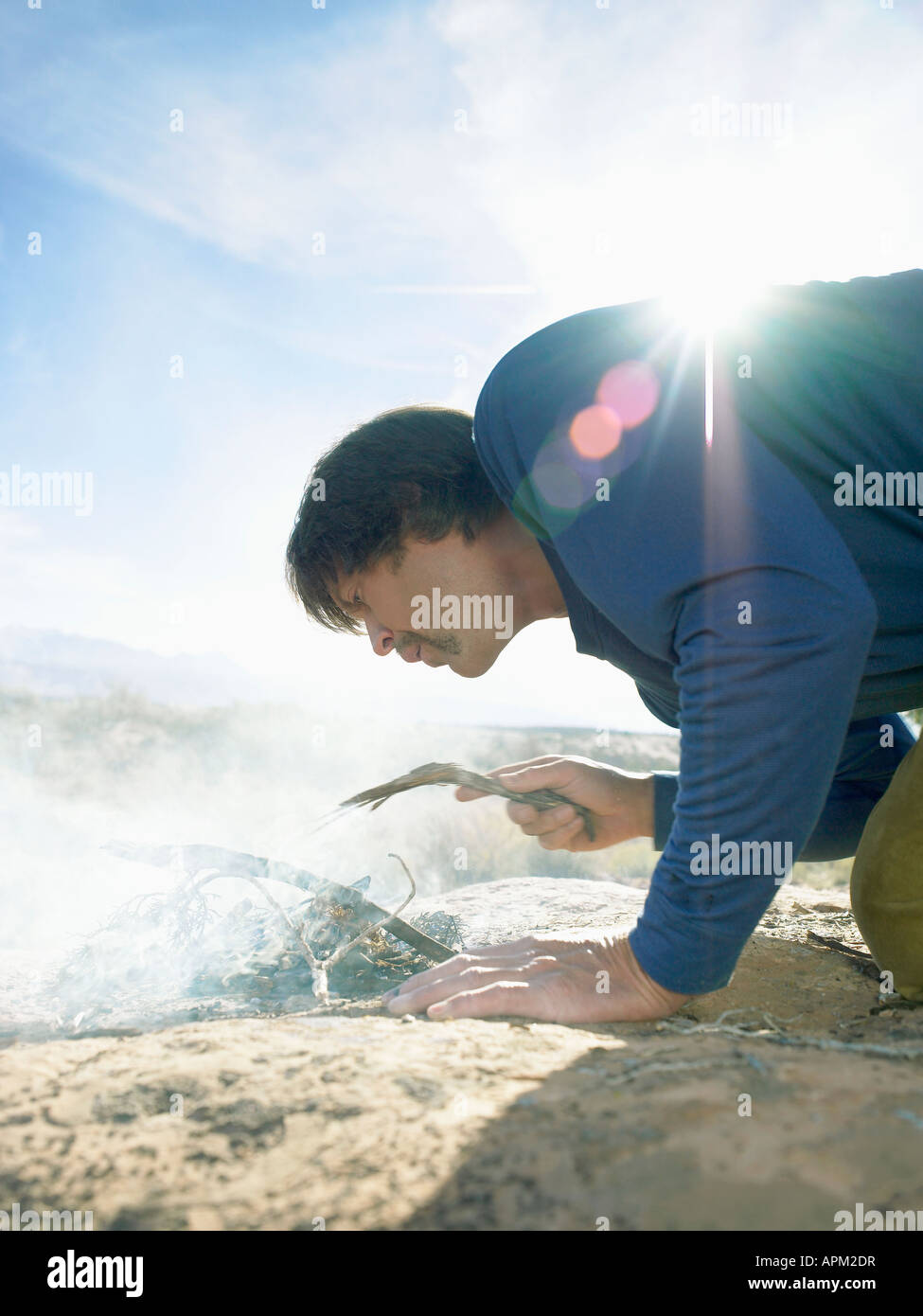 Man lighting fire on rock, low angle view Stock Photo - Alamy