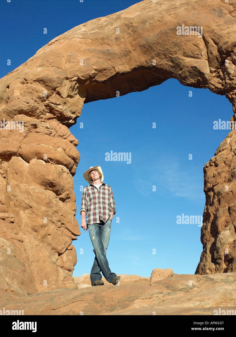 Young man standing under arched rock Stock Photo - Alamy