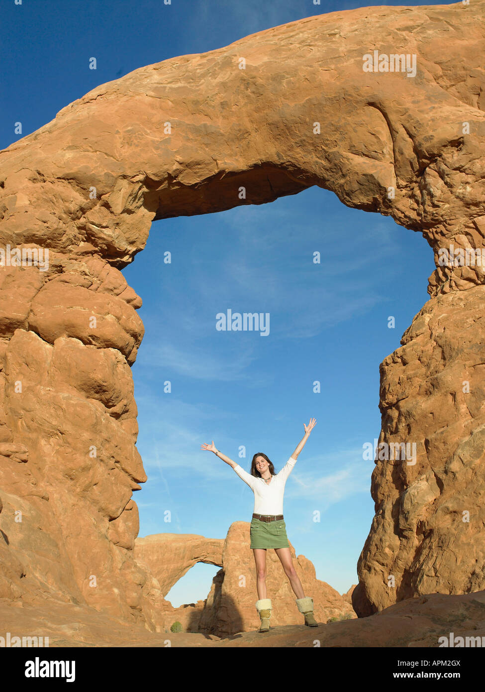 Young woman standing under arched rock Stock Photo - Alamy