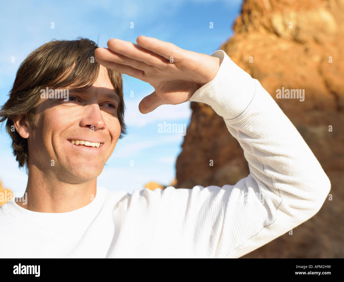 Mid adult man looking into distance with hand shadowing eyes Stock ...