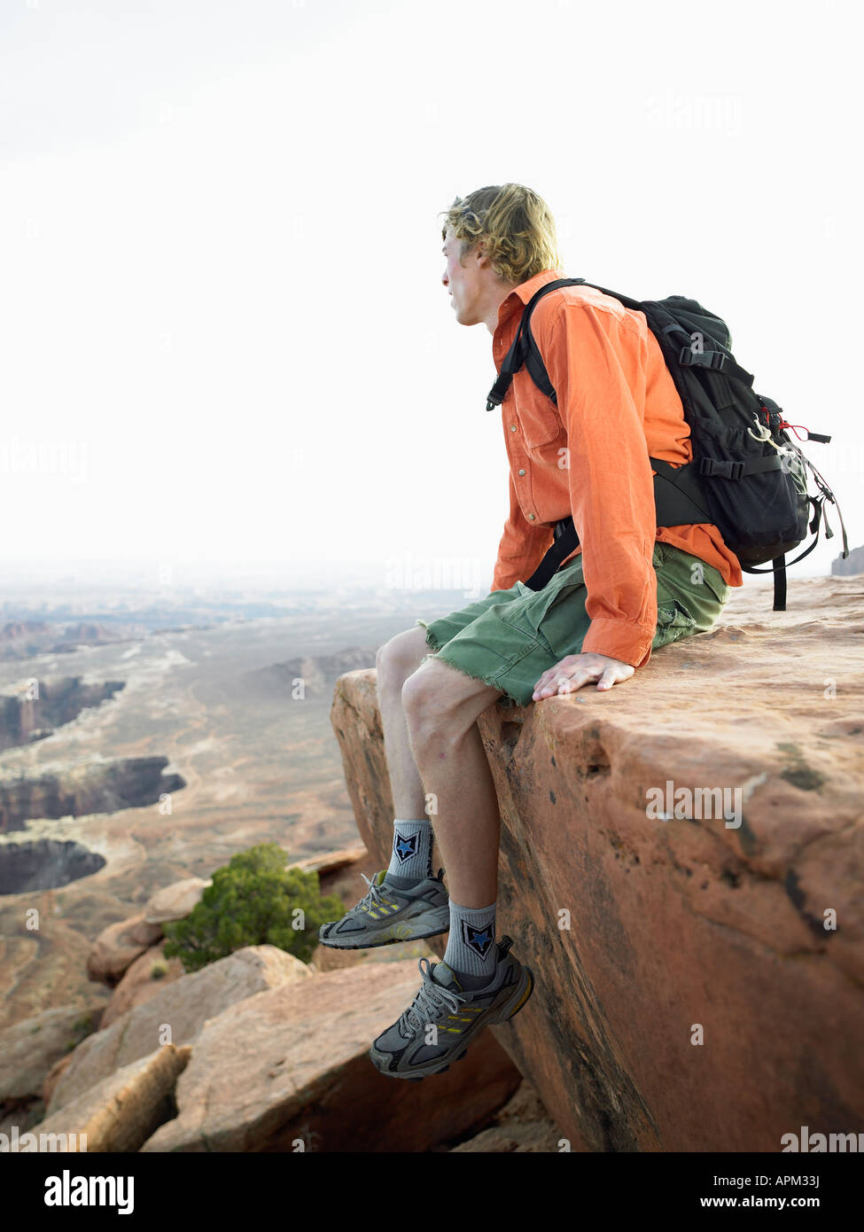 Male hiker sitting on cliff Stock Photo - Alamy