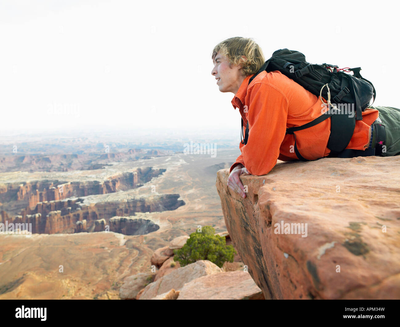 Young man with backpack lying on cliff Stock Photo - Alamy