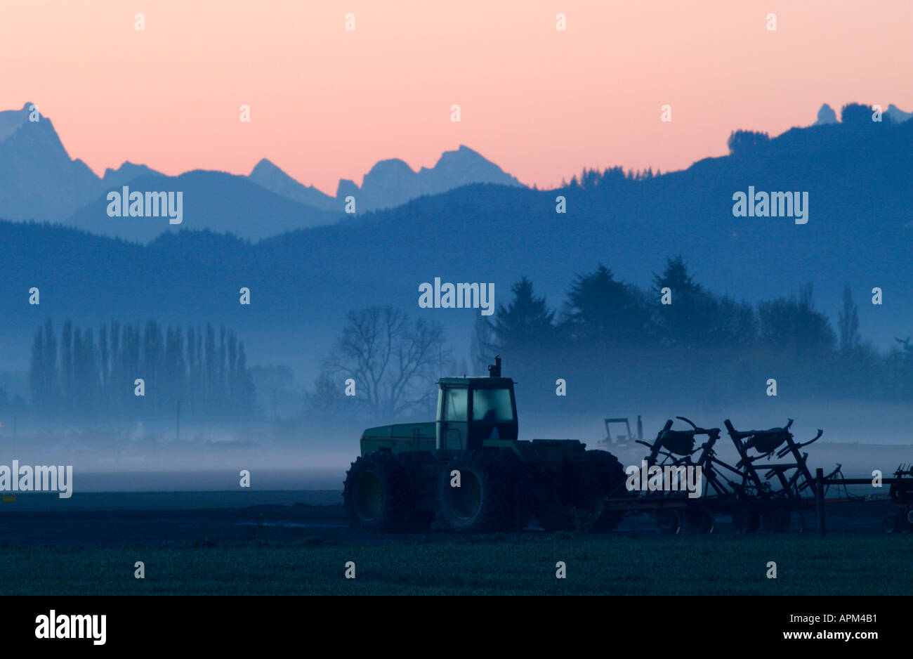 Tractor in field at sunrise with Cascade Mountains in background Mount ...
