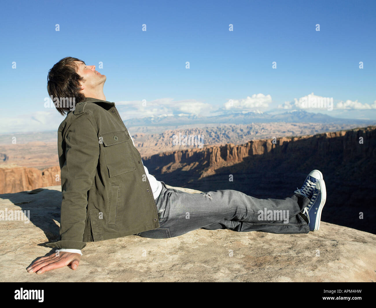 Mid adult man sitting by cliff Stock Photo - Alamy