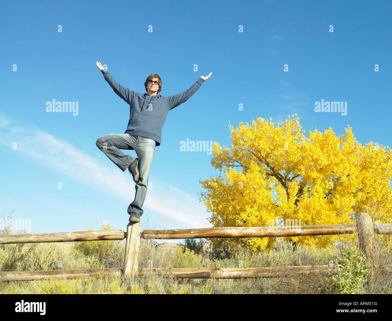 Man standing on pole of fence, portrait, low angle view Stock Photo - Alamy