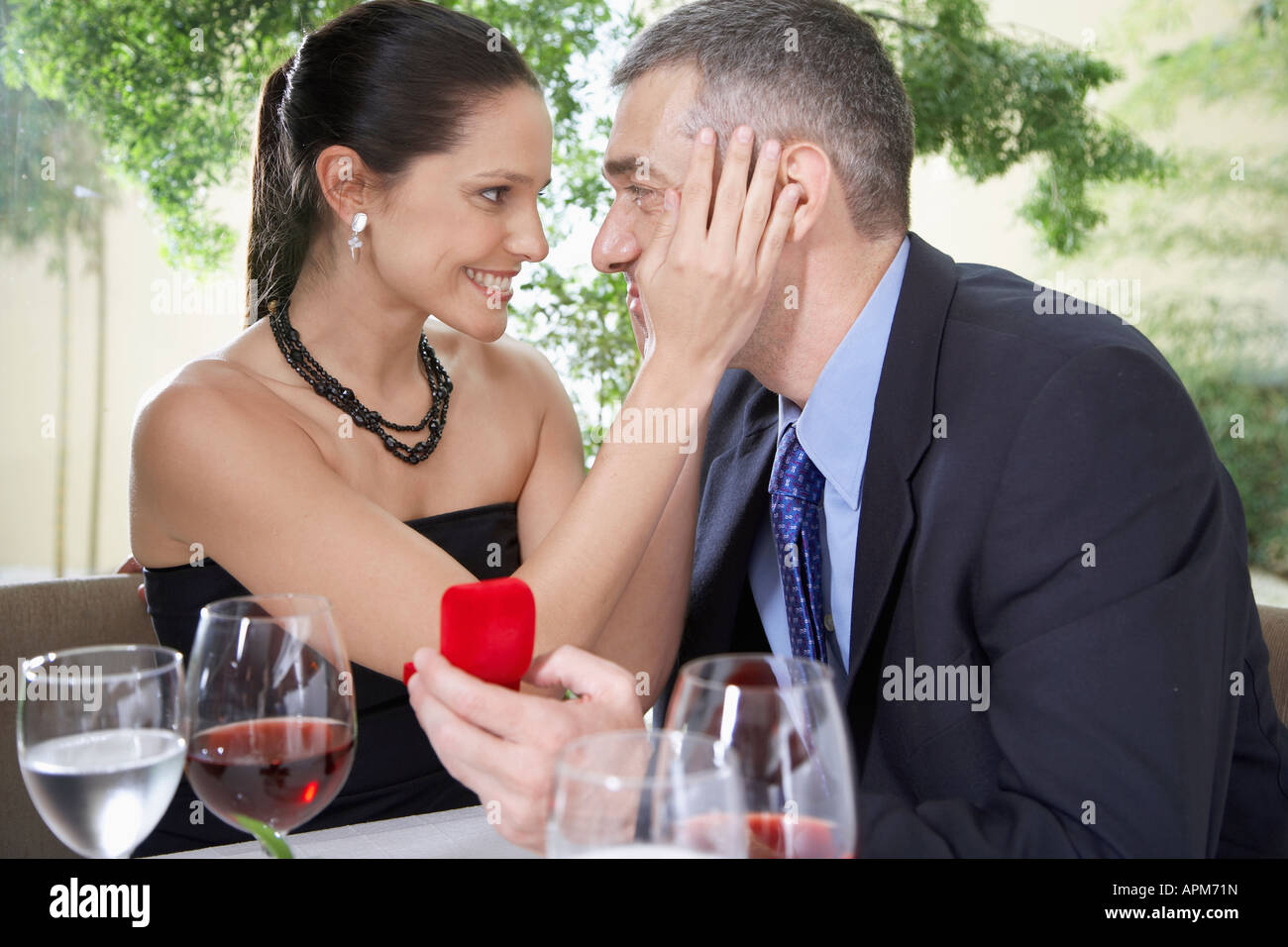 Woman touching man's face, man holding gift Stock Photo - Alamy