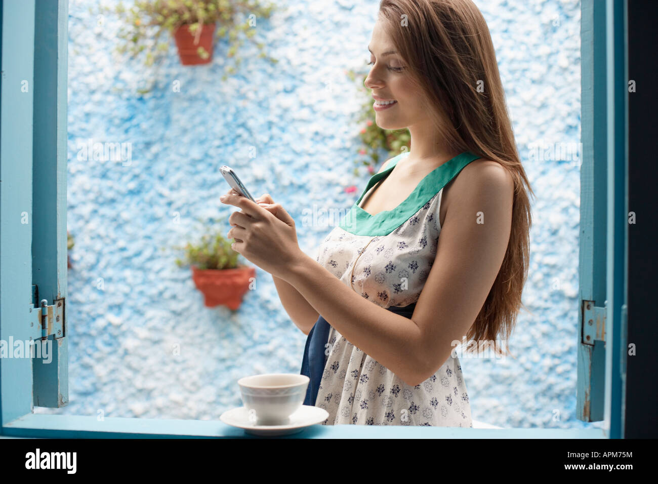 Woman text messaging by window Stock Photo - Alamy