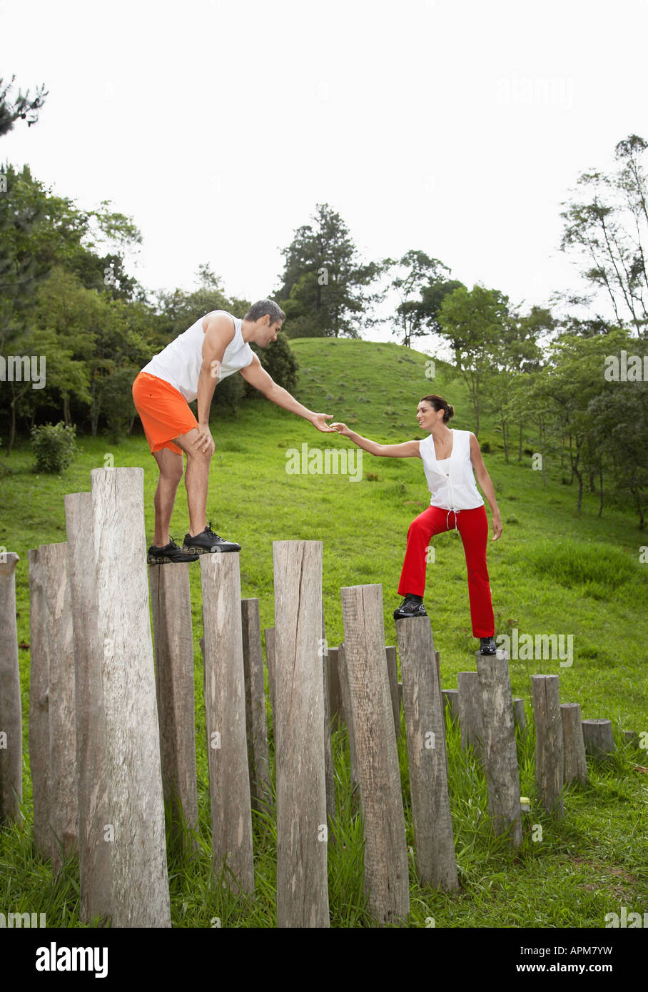 Man helping woman to climb tree stumps Stock Photo - Alamy