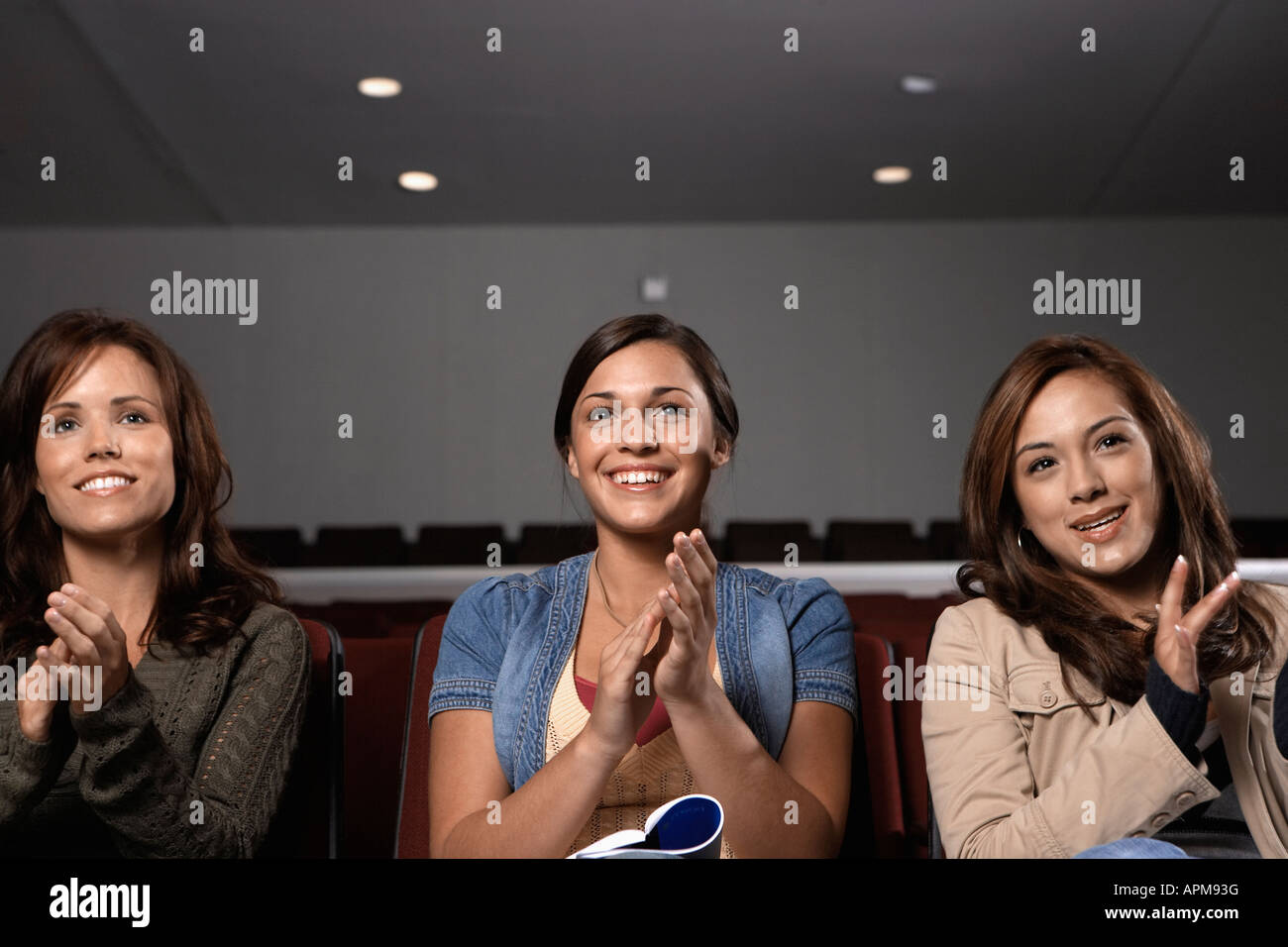 Three female students clapping in lecture theater Stock Photo - Alamy
