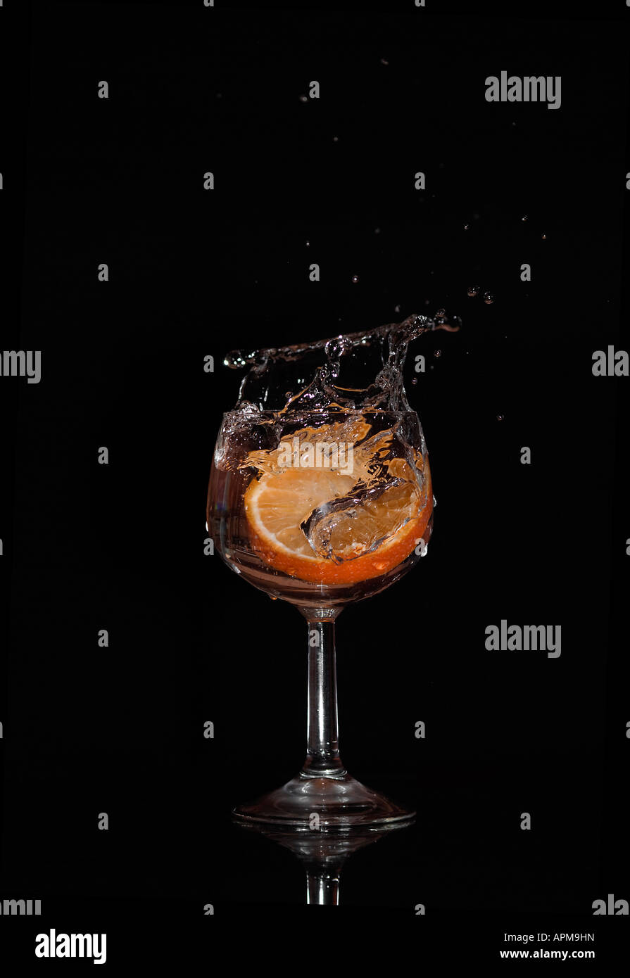 Orange slice dropping into drink, black background Stock Photo - Alamy