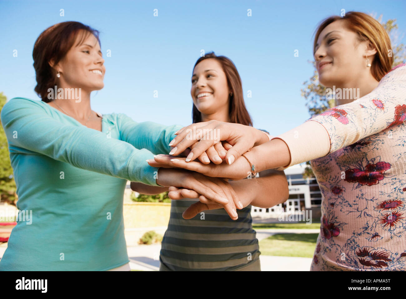 Three young women putting hands together Stock Photo - Alamy