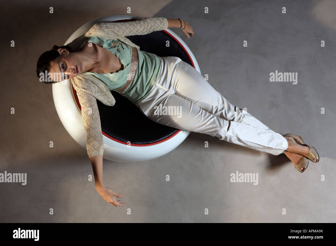 Woman lying down on round chair Stock Photo - Alamy