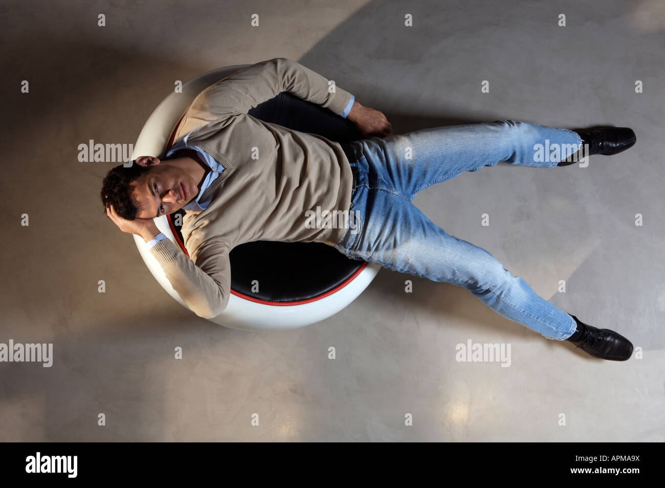 Man lying down on round chair Stock Photo - Alamy