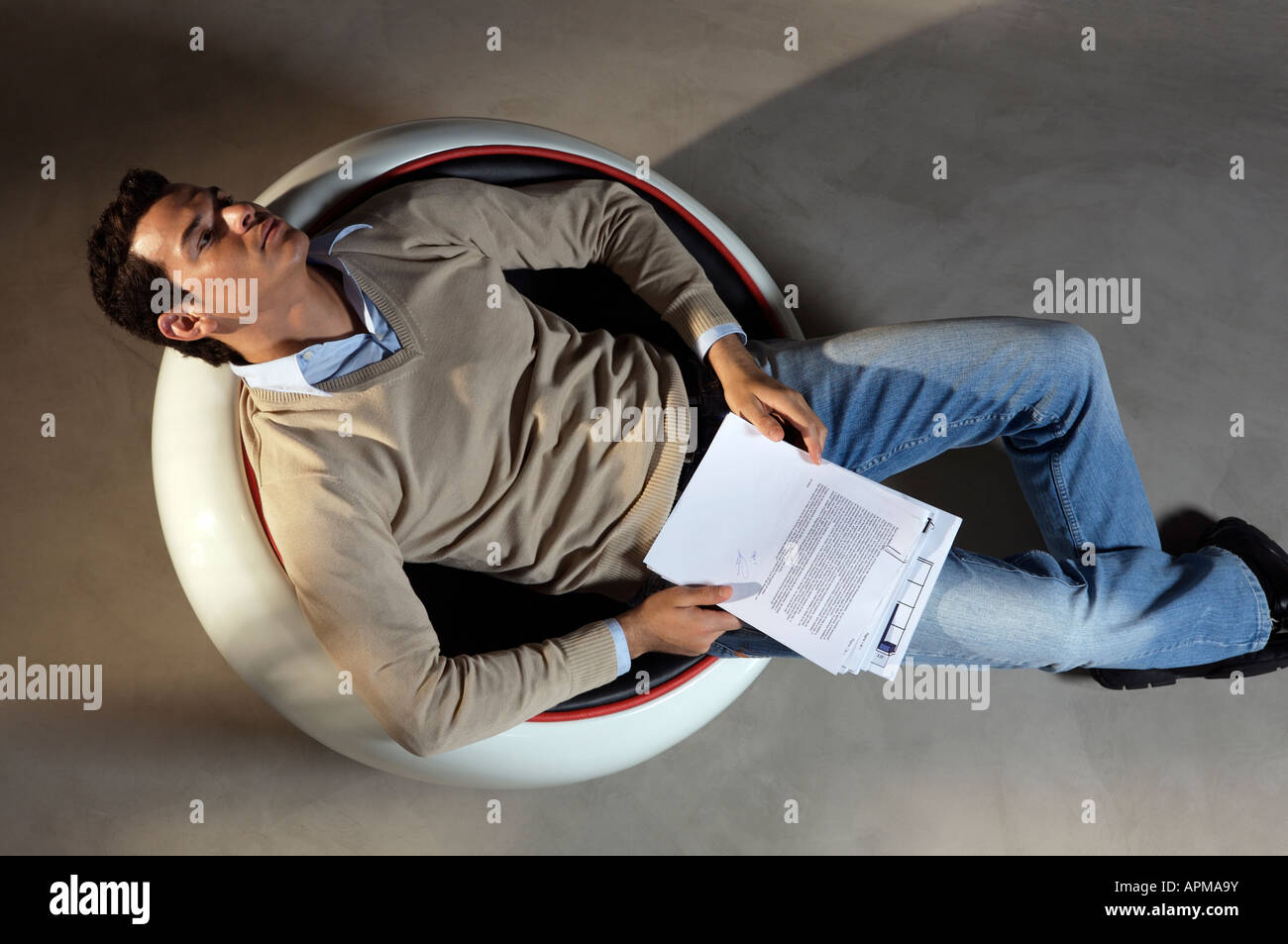 Man lying down on round chair Stock Photo - Alamy