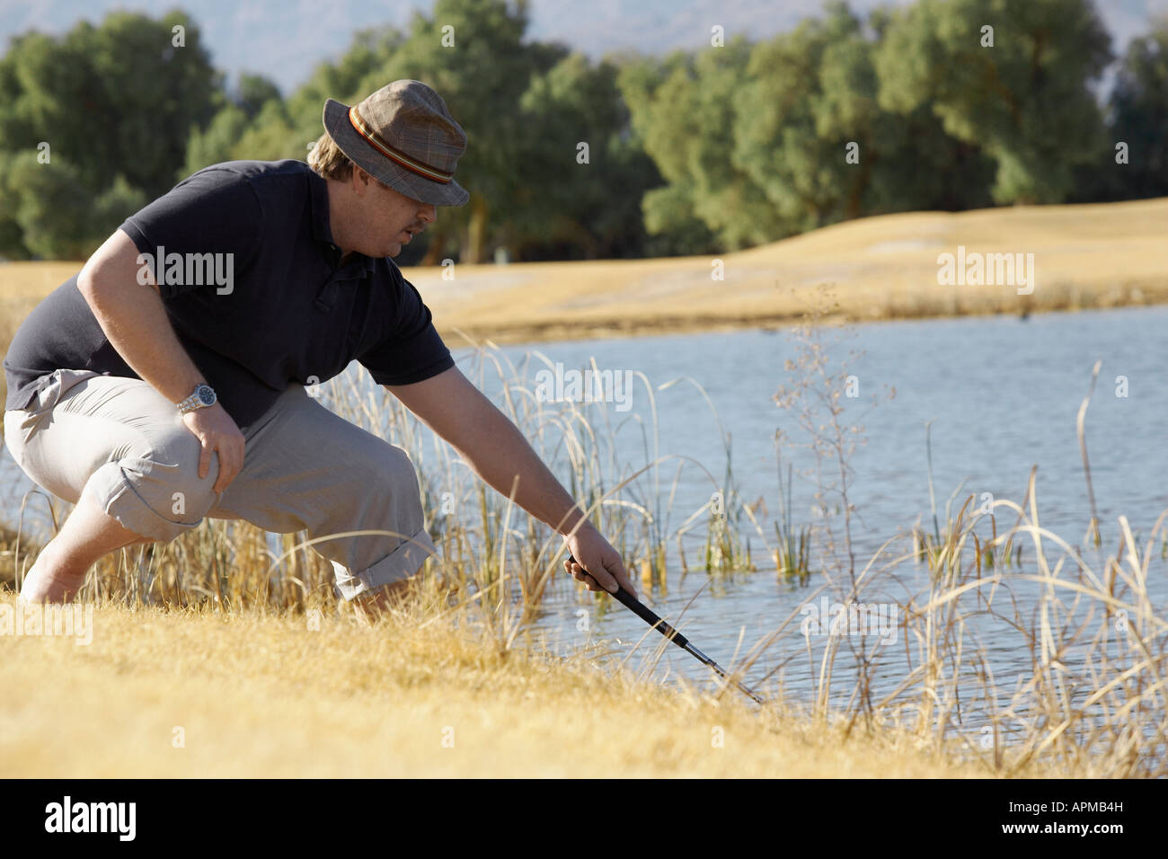 Man looking for golf ball in pond Stock Photo - Alamy