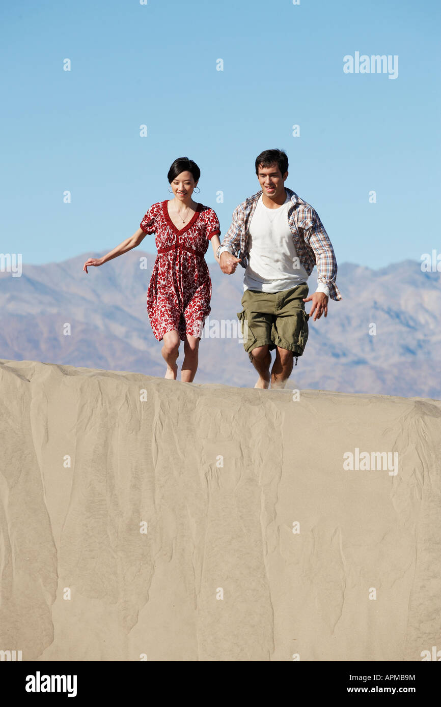 Couple walking on sand dunes Stock Photo - Alamy
