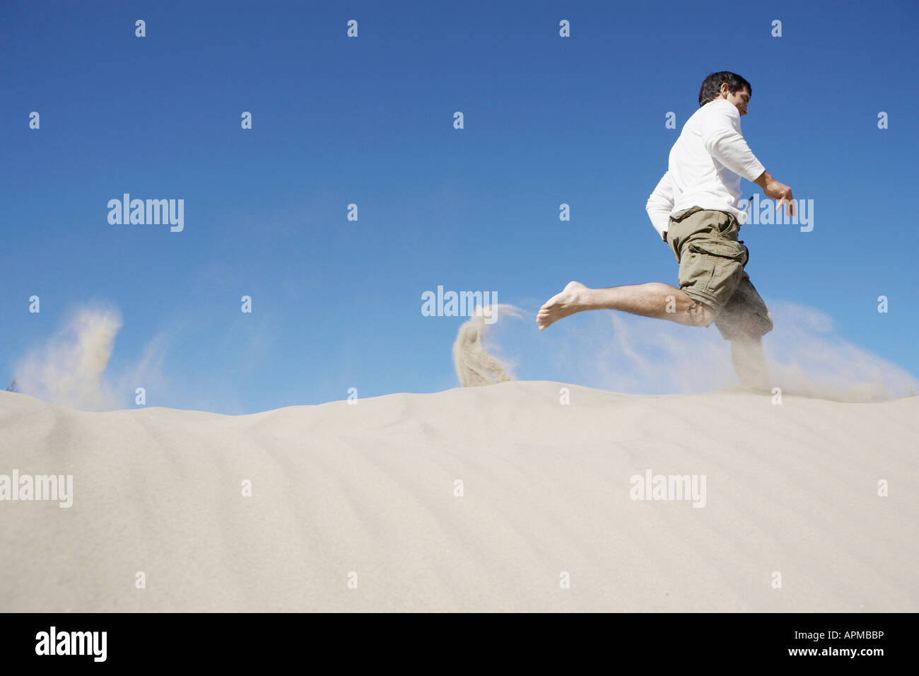 Man running on sand dune (low angle view Stock Photo - Alamy