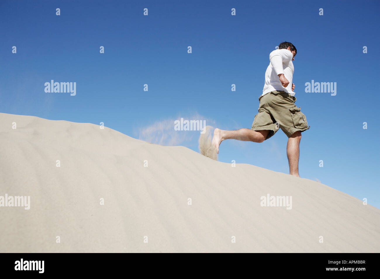 Man running on sand dune (low angle view Stock Photo - Alamy