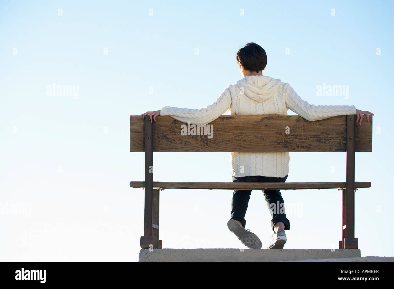 Young woman sitting on bench and looking at view (rear view Stock Photo ...
