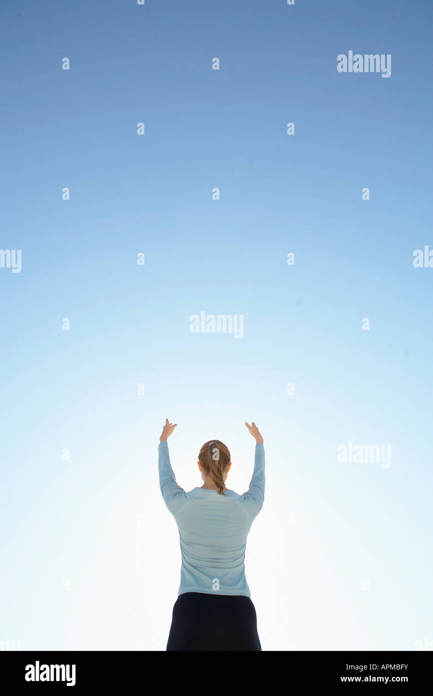 Young woman with raised arms against clear sky (rear view, low angle ...