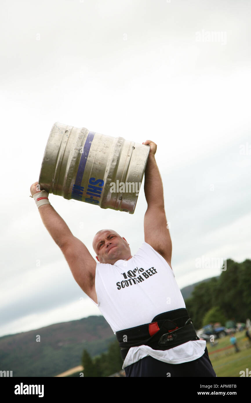 Portrait of strong muscular, athletic man lifting heavy cask at ...