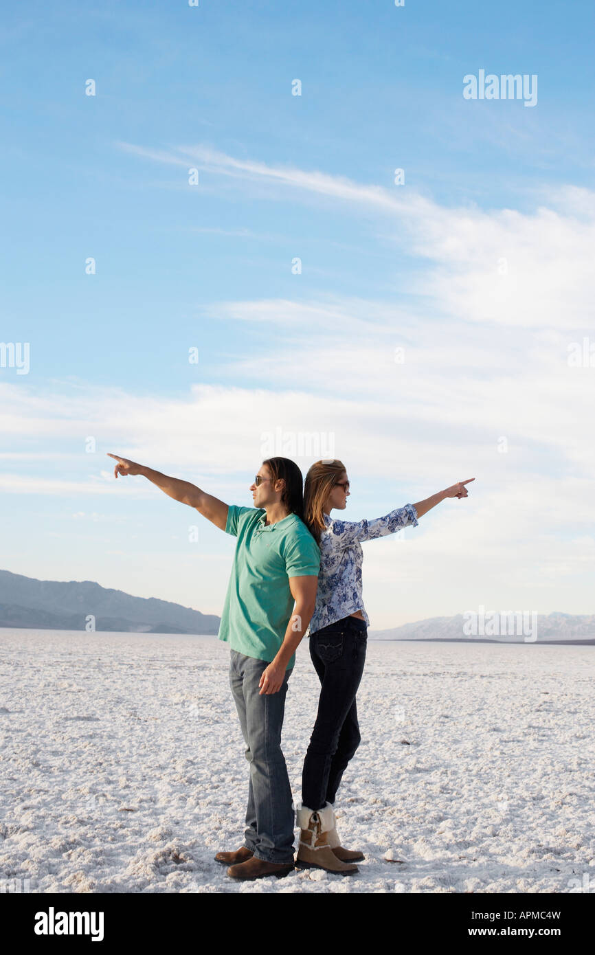Couple standing back to back and pointing to opposite directions in ...