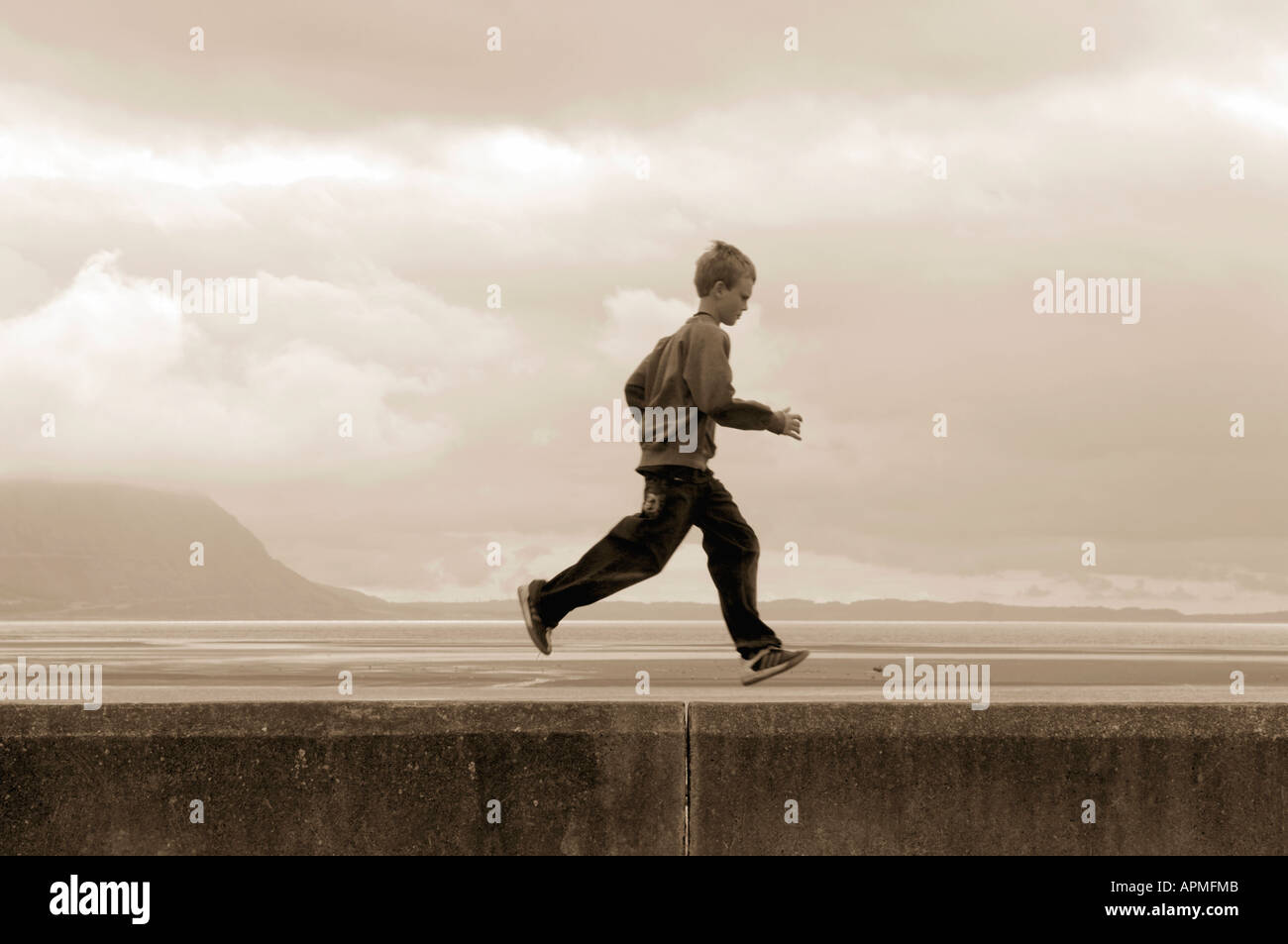 Boy Running Across A Coastal Wall Stock Photo - Alamy