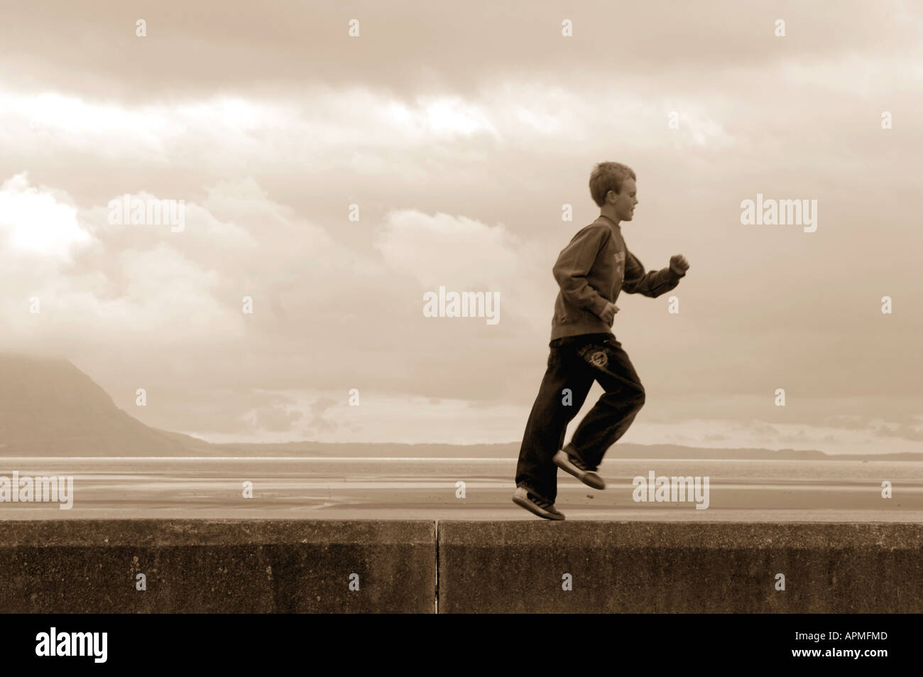 Boy Running Across A Coastal Wall Stock Photo - Alamy