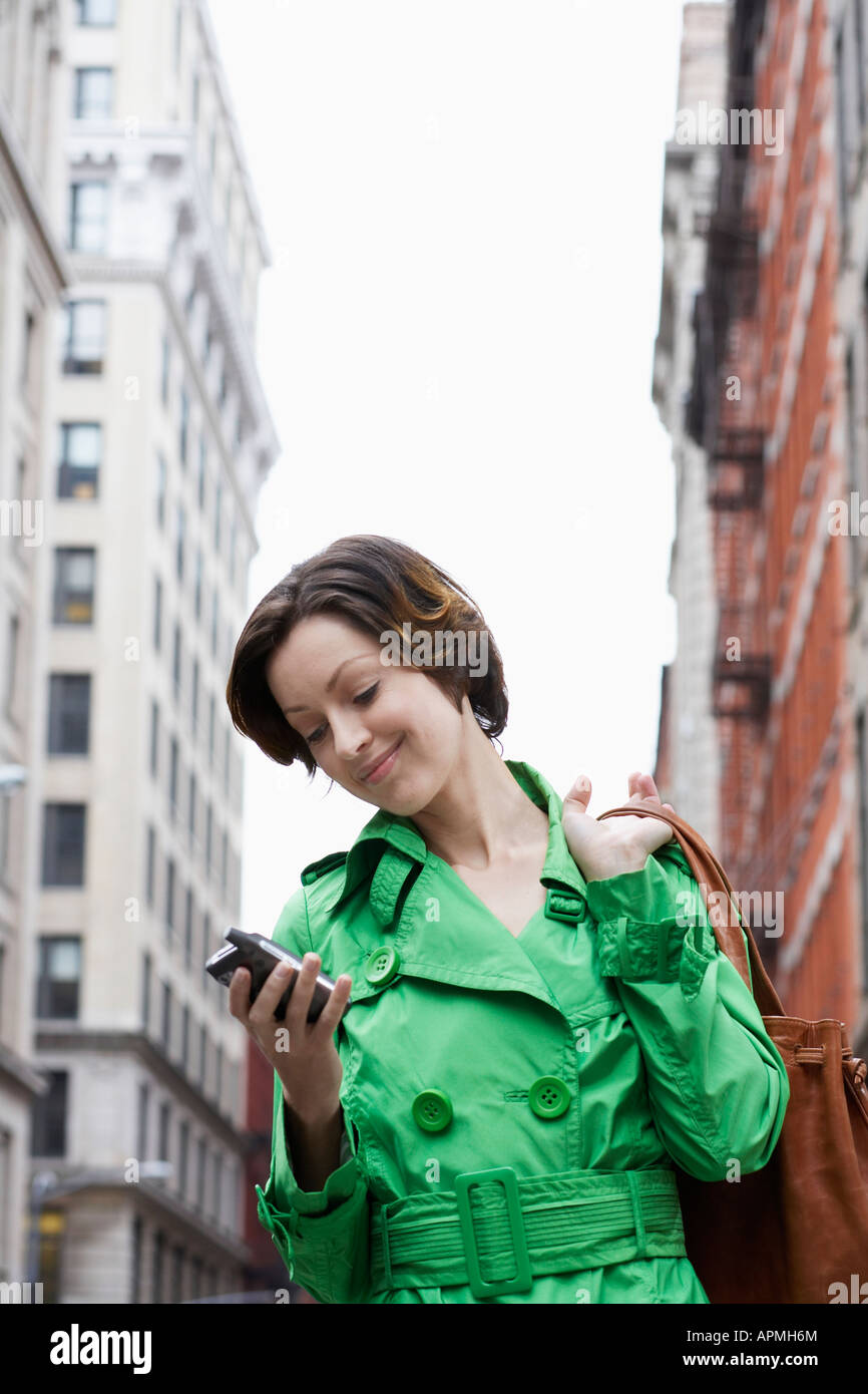 Mid adult woman using PDA on street, low angle view Stock Photo - Alamy