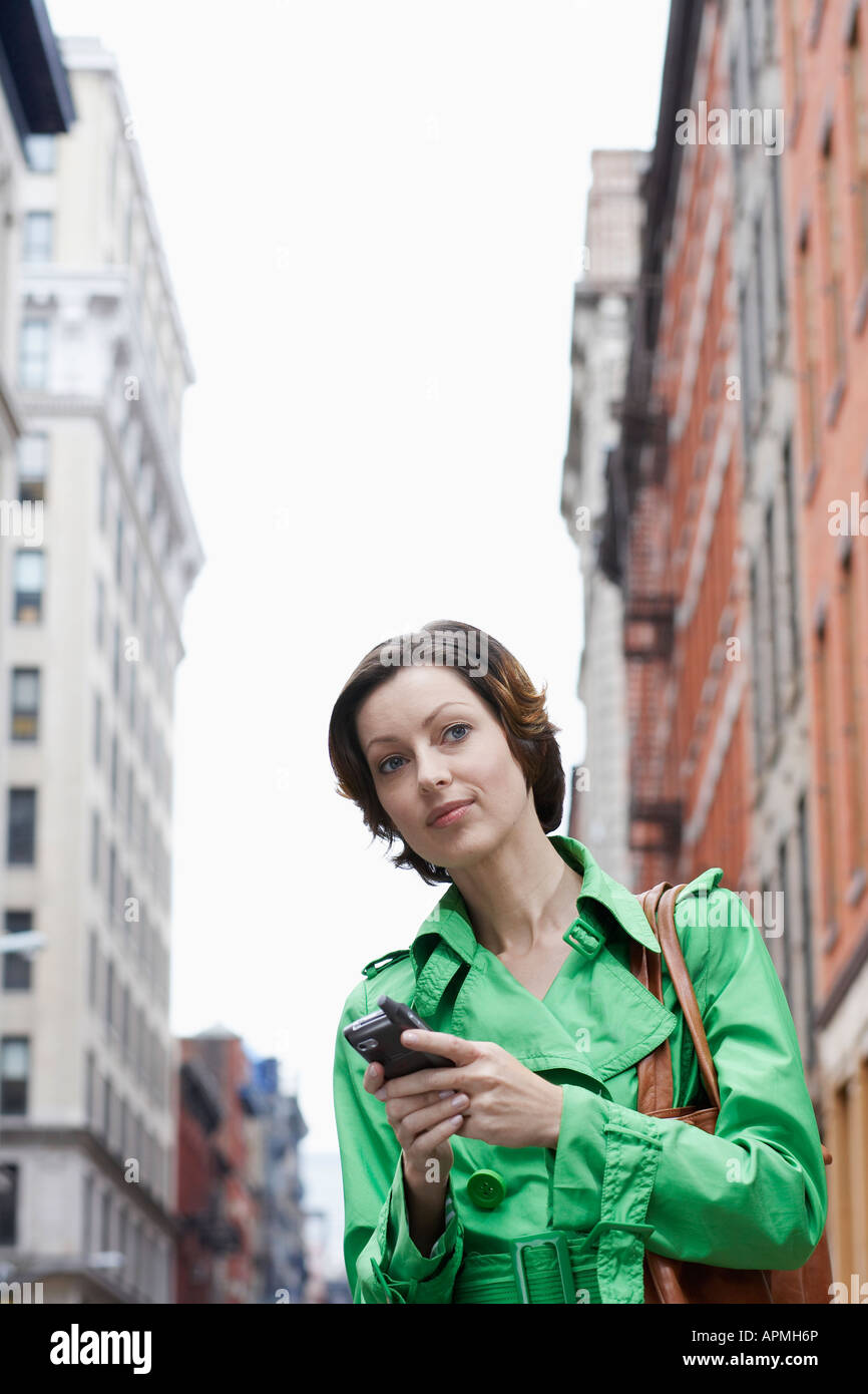 Mid adult woman using PDA on street Stock Photo - Alamy