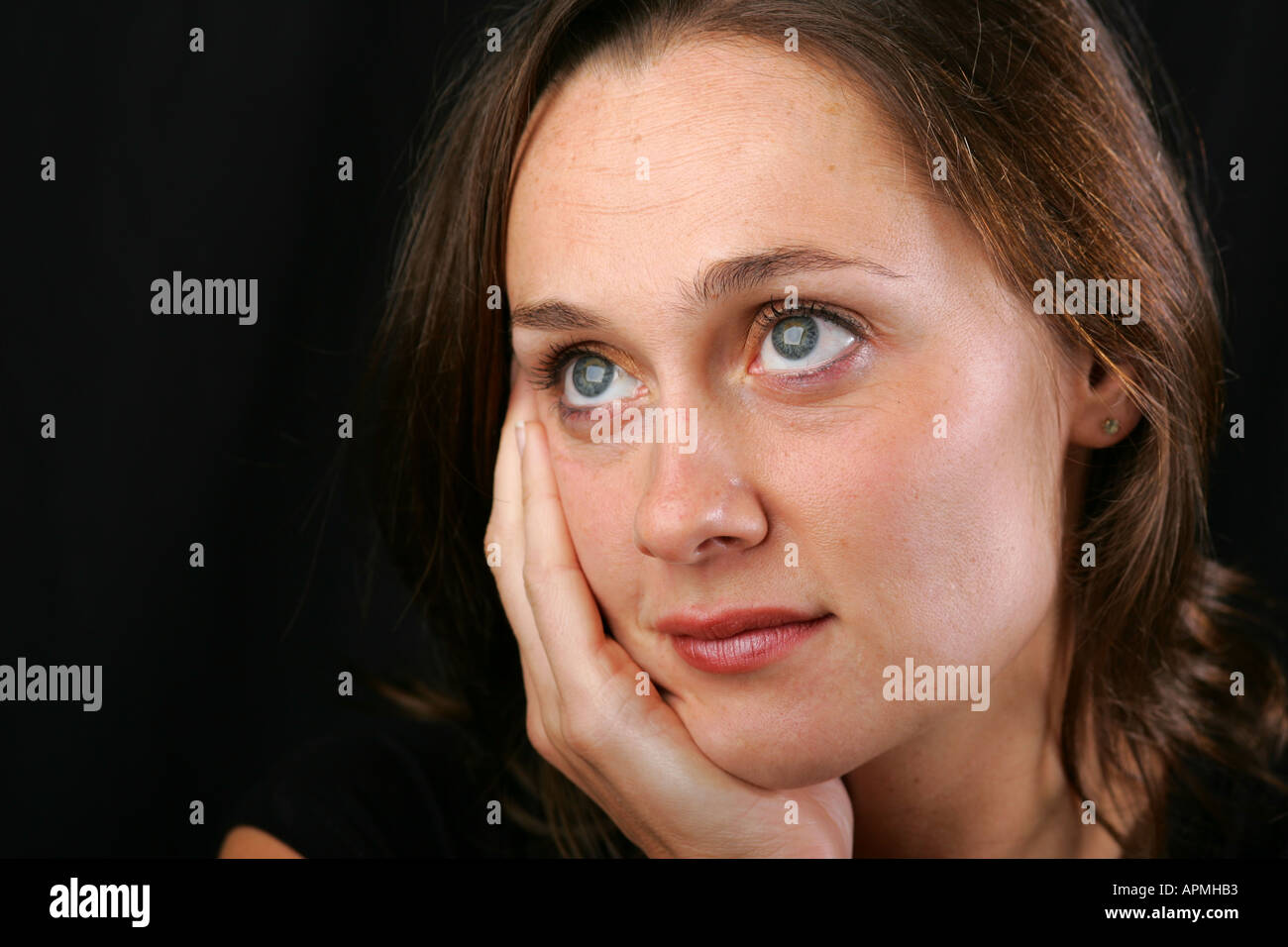 Brunette woman hand on cheek contented happy relaxed distant wistful ...