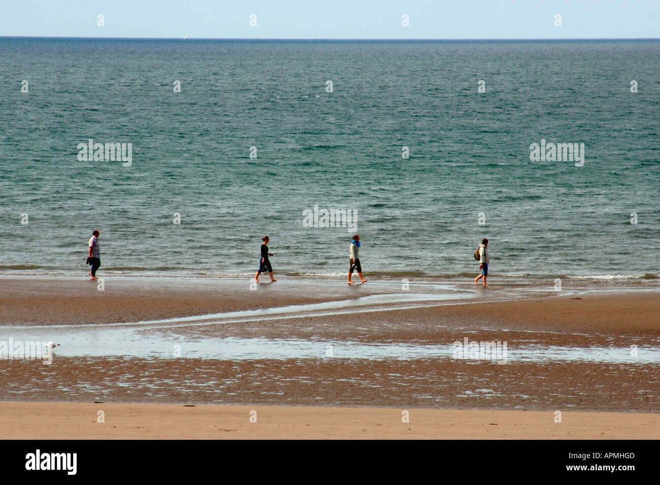 People Walking Across A Welsh Beach Stock Photo - Alamy