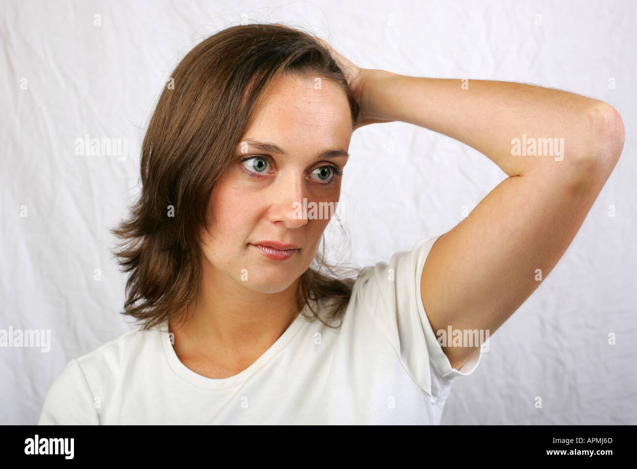 Attractive young 20s 30s brunette woman runs a hand through her hair ...